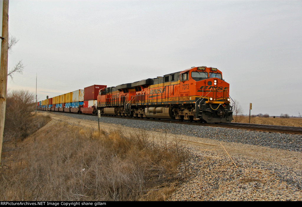 BNSF 7373 hurries a WB stack train.